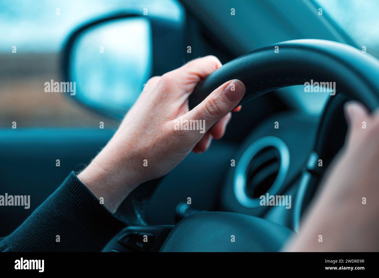 Female hands on car steering wheel. Woman driver traveling along the ...