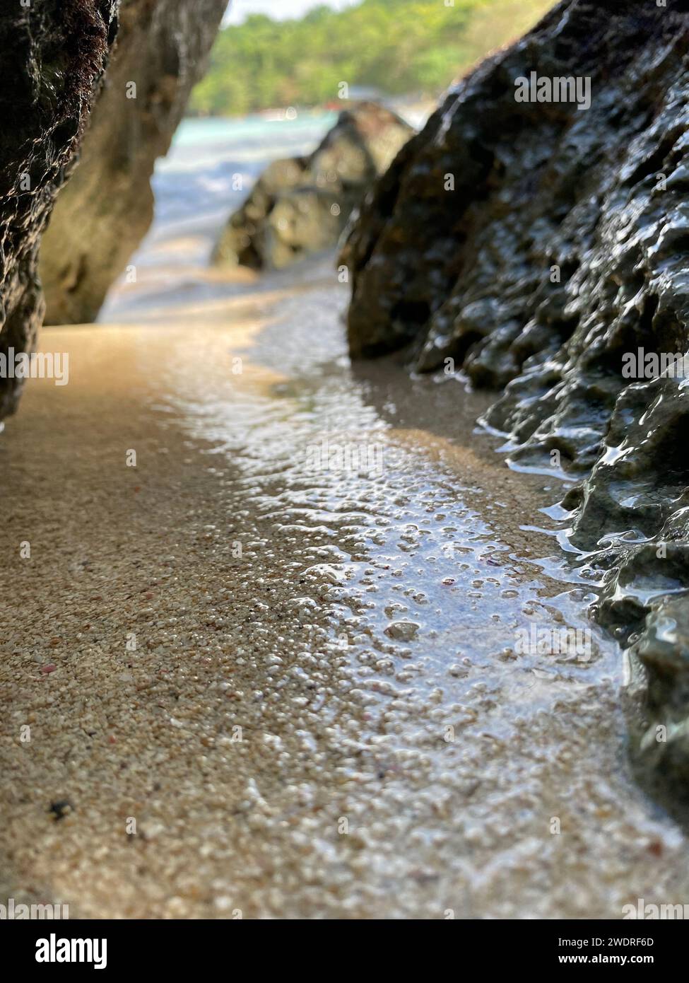 Water flowing out of a crevice in the sand on a serene beach Stock ...