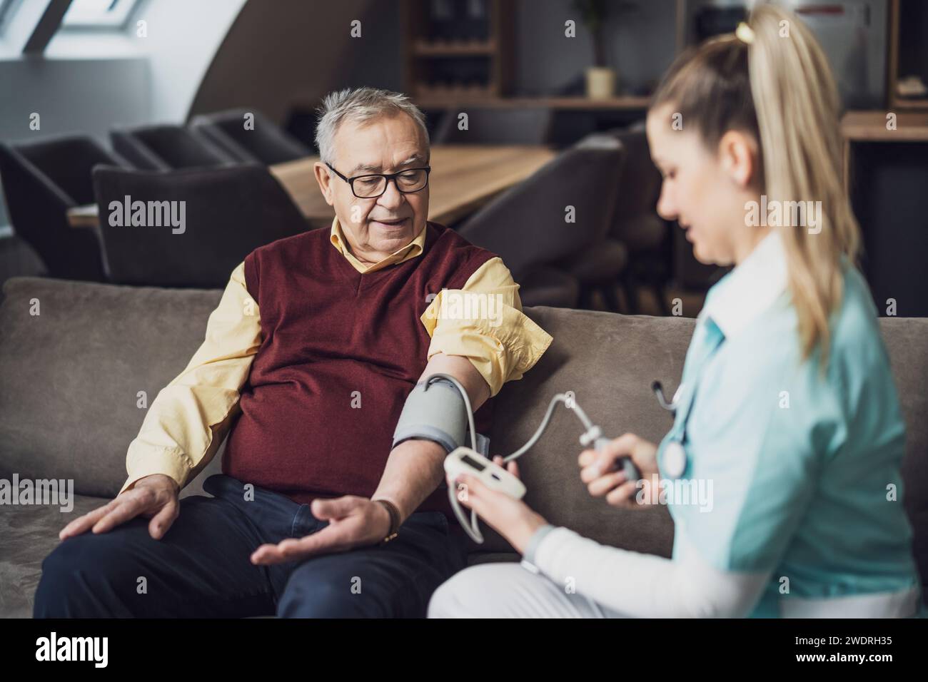 Home doctor is measuring blood pressure of old man at his home ...