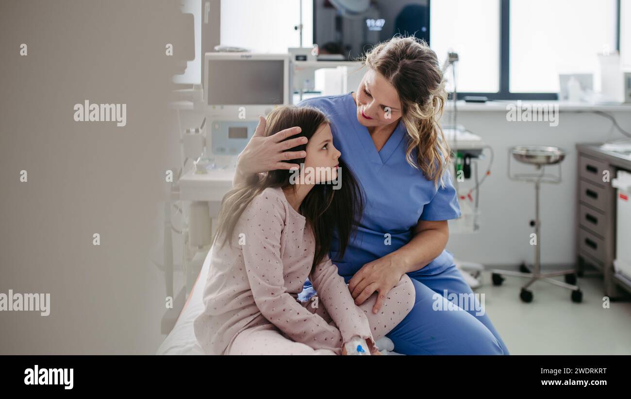 Supportive doctor soothing a worried children patient in emergency room ...