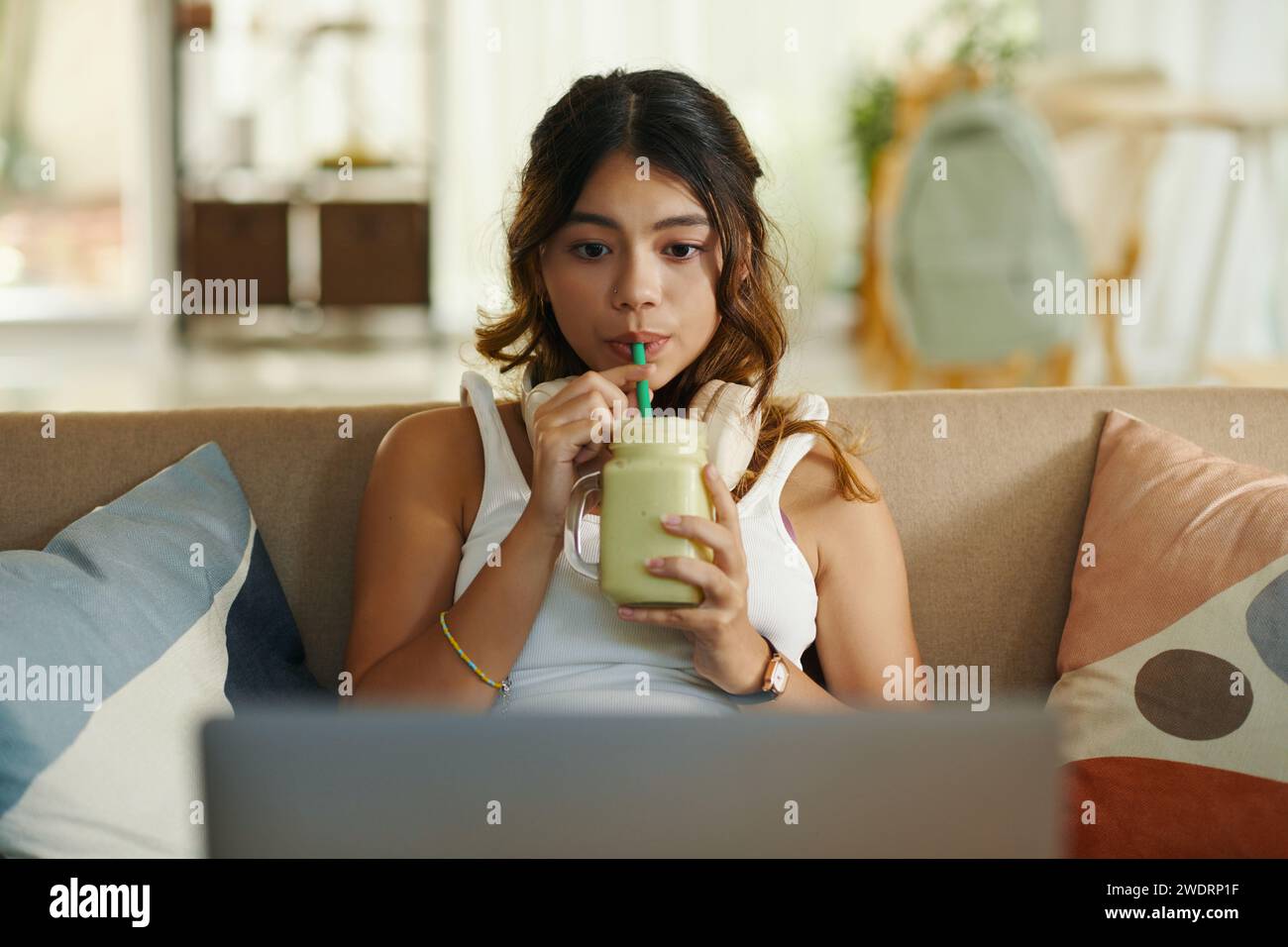 Zoomer girl sipping smoothie and and watching show on laptop Stock ...