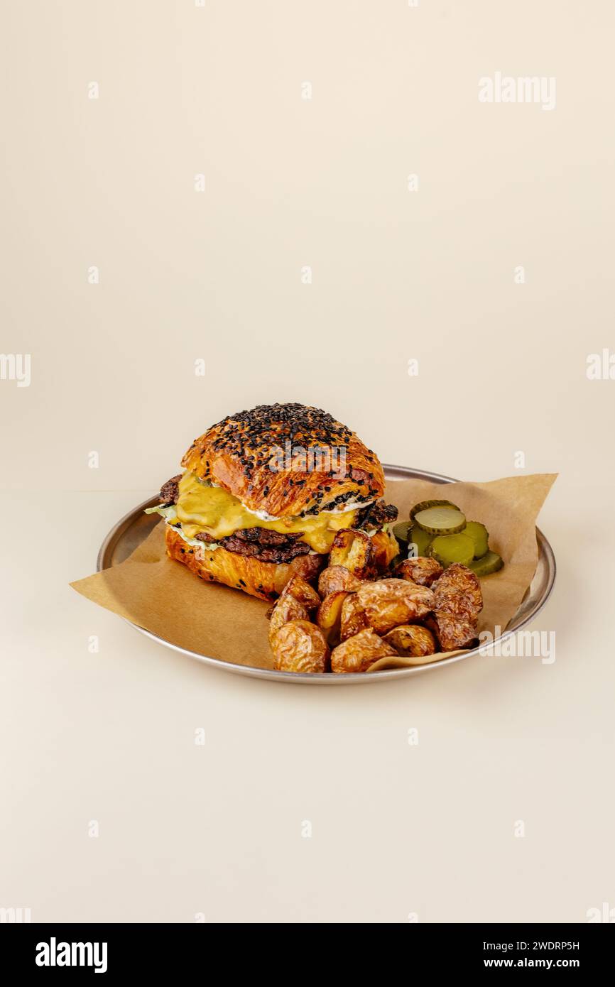 burger with beef patty, cheese sauce on a plate with potatoes Stock ...