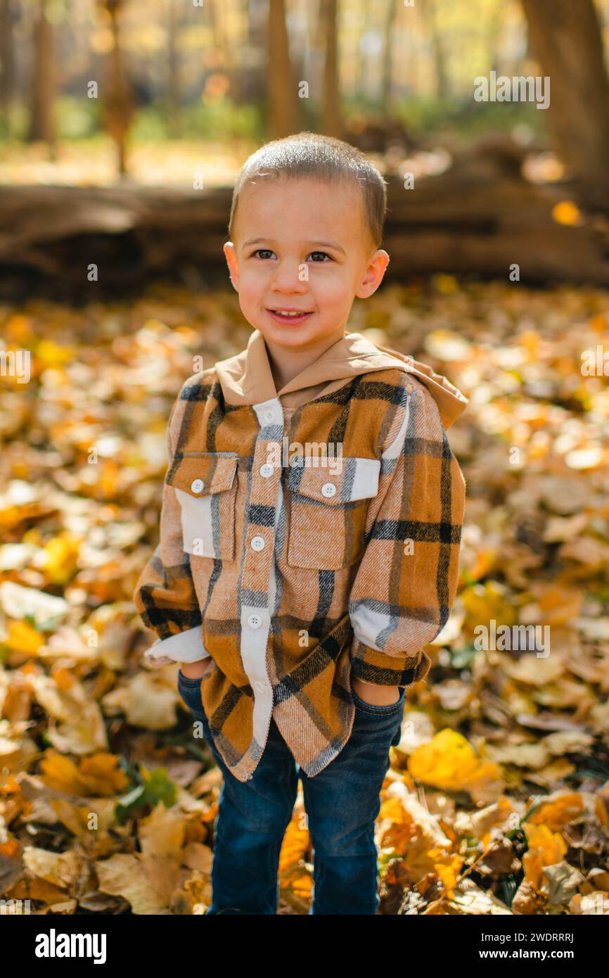 Portrait of young happy child with hands in pockets in fall foliage ...