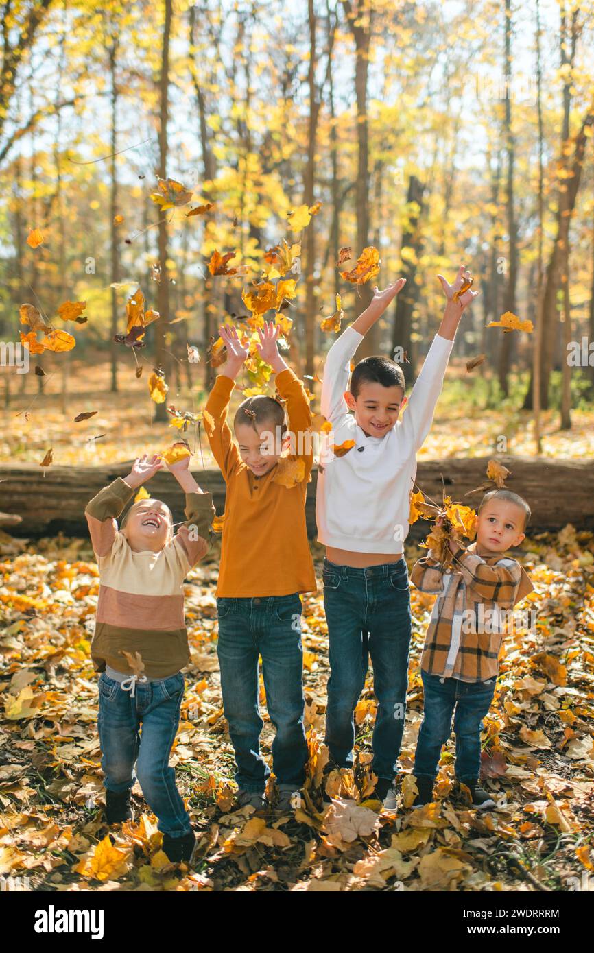 Happy siblings throwing yellow autumn leaves together in sunny forest ...