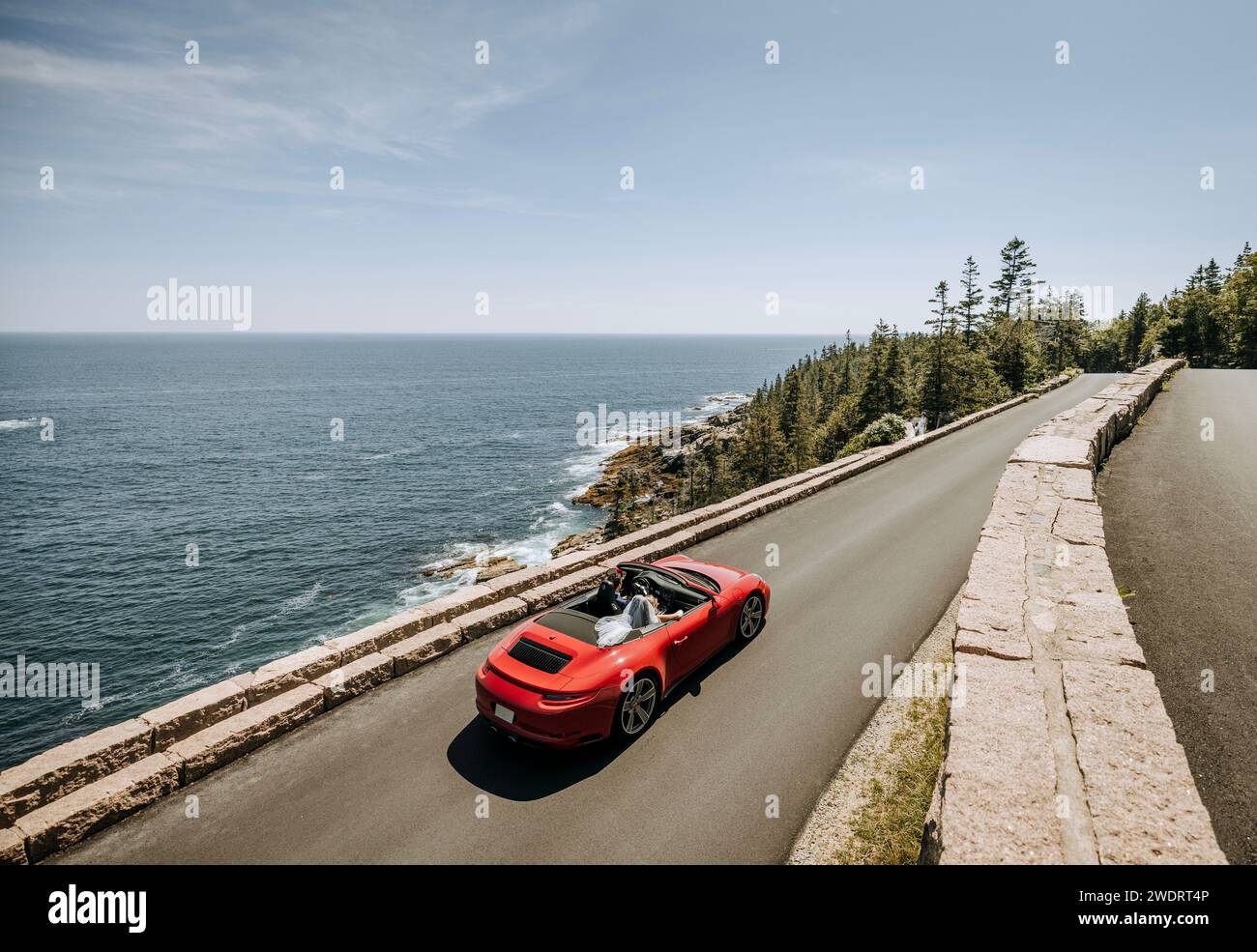 Newlywed couple drive red convertible sports car along ocean Stock ...