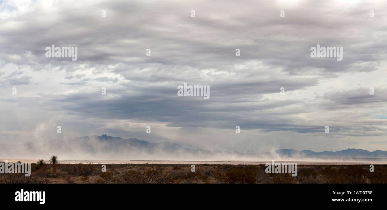 Dust storm swells around a train in the far distant desert landscape ...