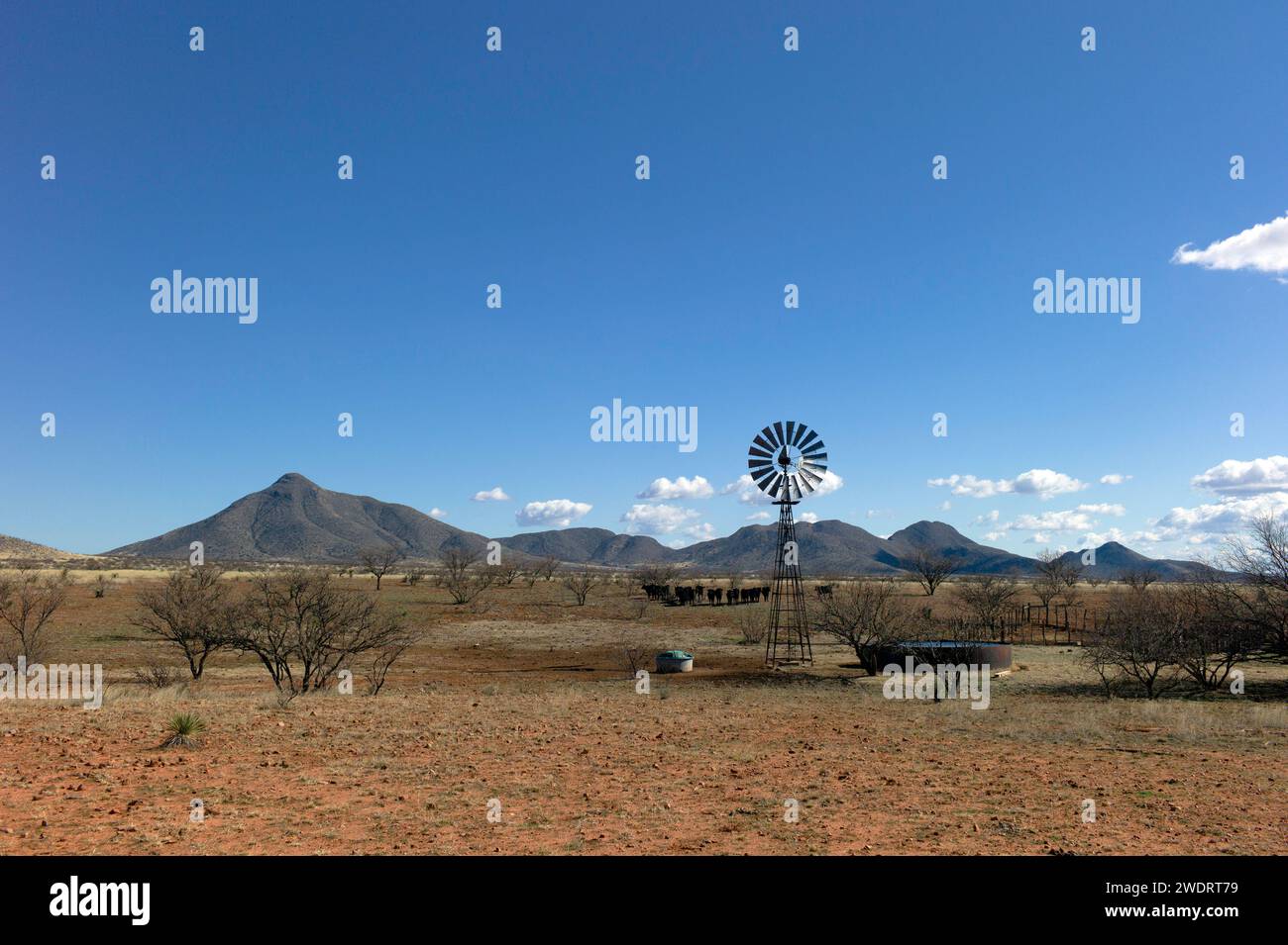 Old western windmill on a desert ranch, small mountains in distance ...