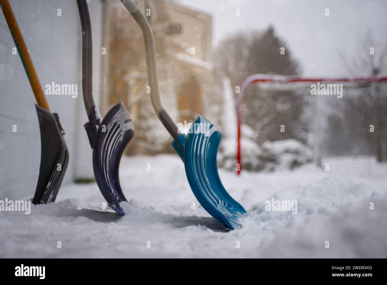 3 shovels resting against the side of a house Stock Photo - Alamy