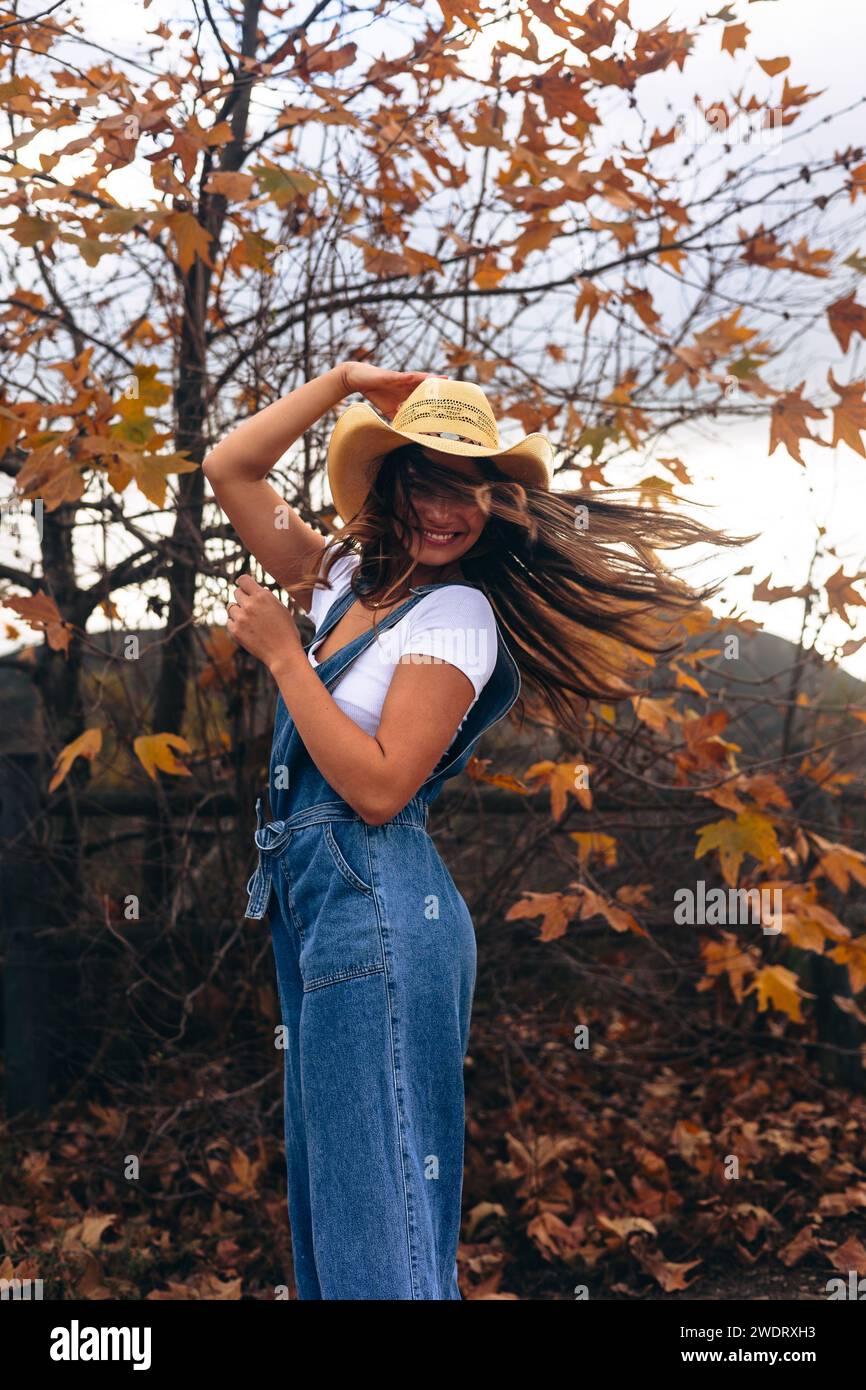 Young woman spinning while holding hat in front of tree in fall Stock ...