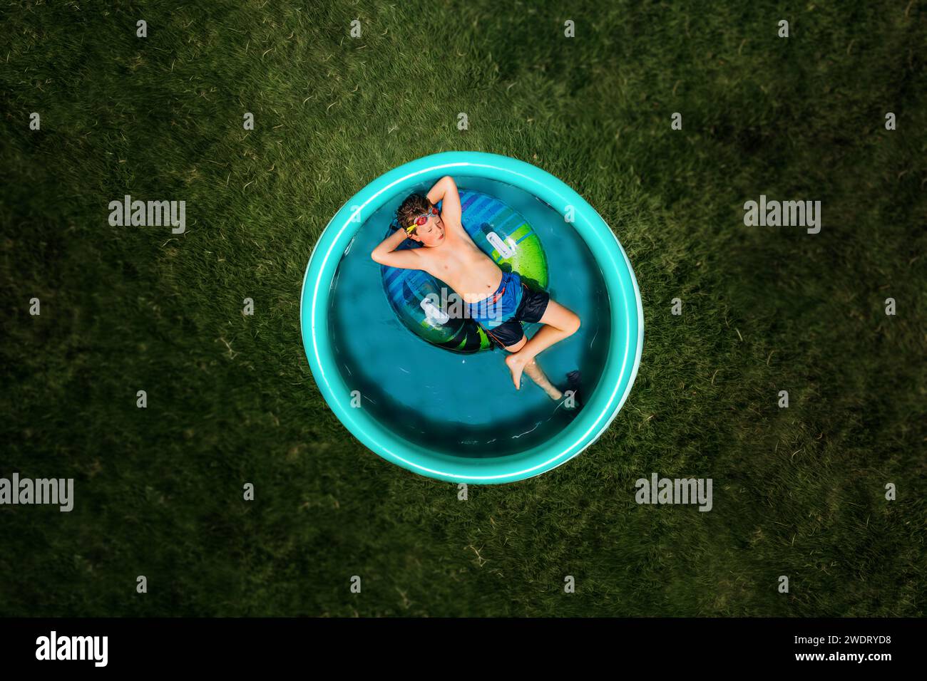 Boy relaxing in small pool in green grass Stock Photo - Alamy