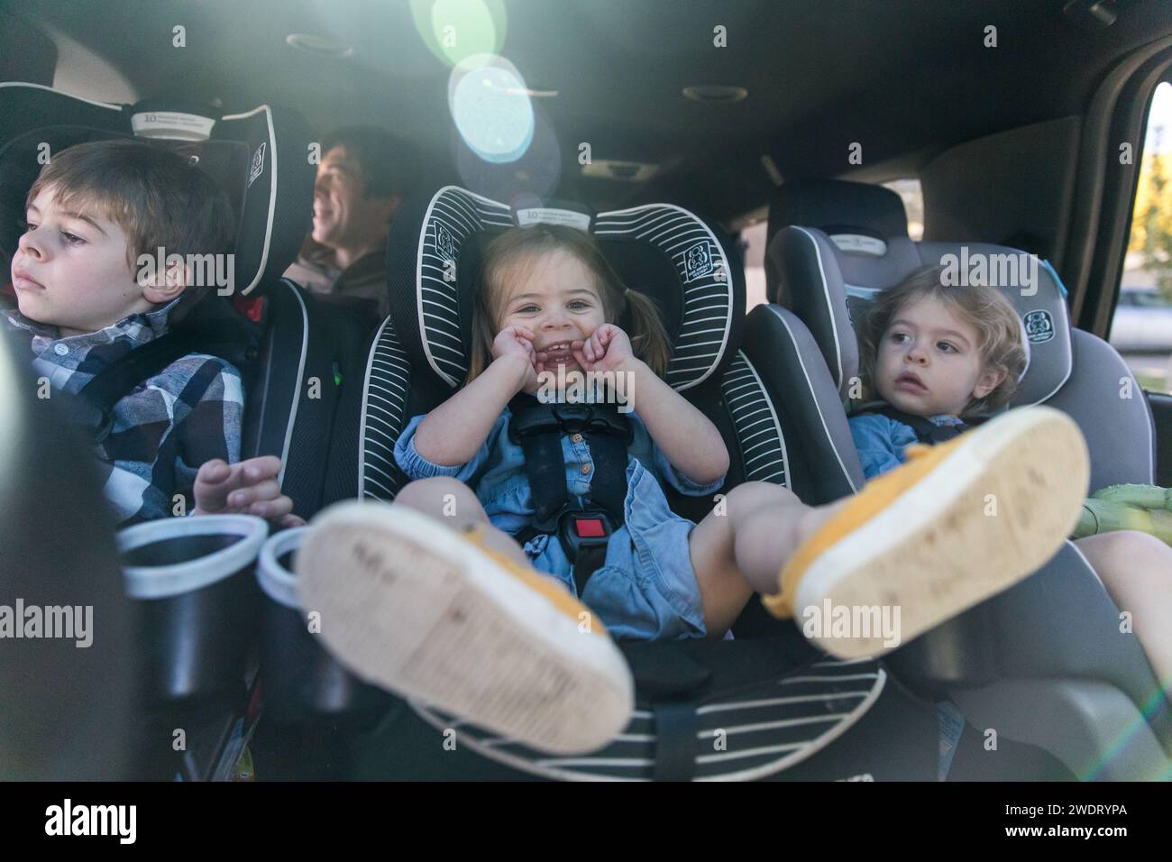 Three siblings strapped into carseats being silly Stock Photo - Alamy