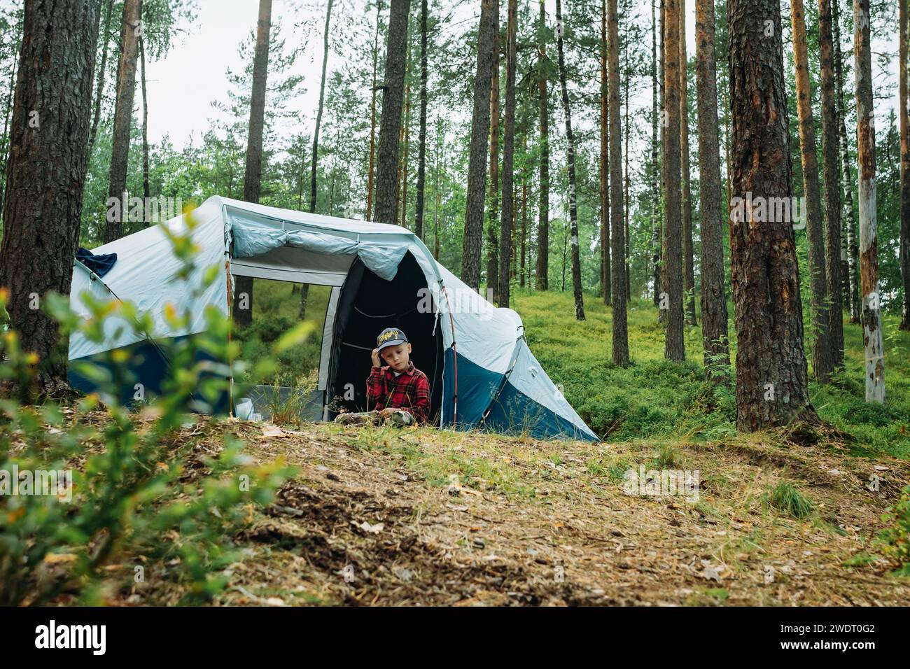 cute caucasian boy wearing hat sitting inside a big touristic tent ...
