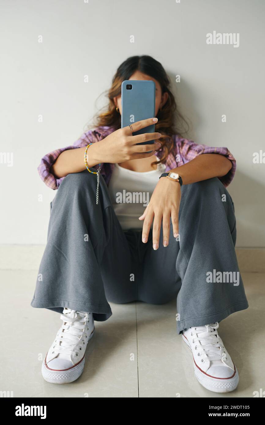 Teenage girl in wide pants, cotton tank top and plaid shirt taking ...
