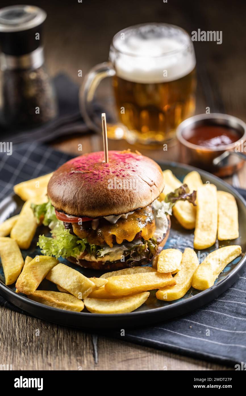 Beef burger with fries and draft beer on a pub or restaurant plate ...