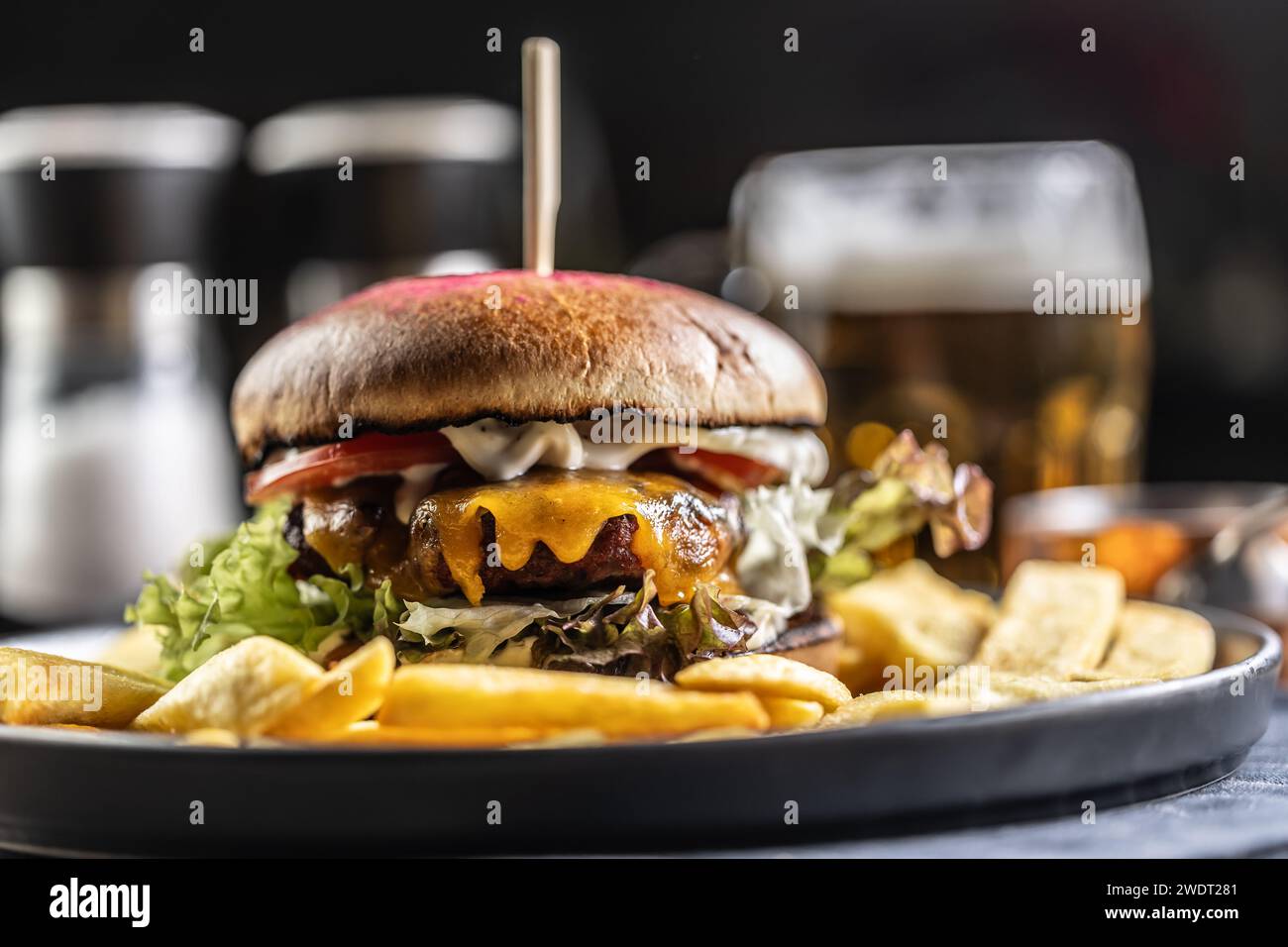 Beef burger with fries and draft beer on a pub or restaurant plate ...