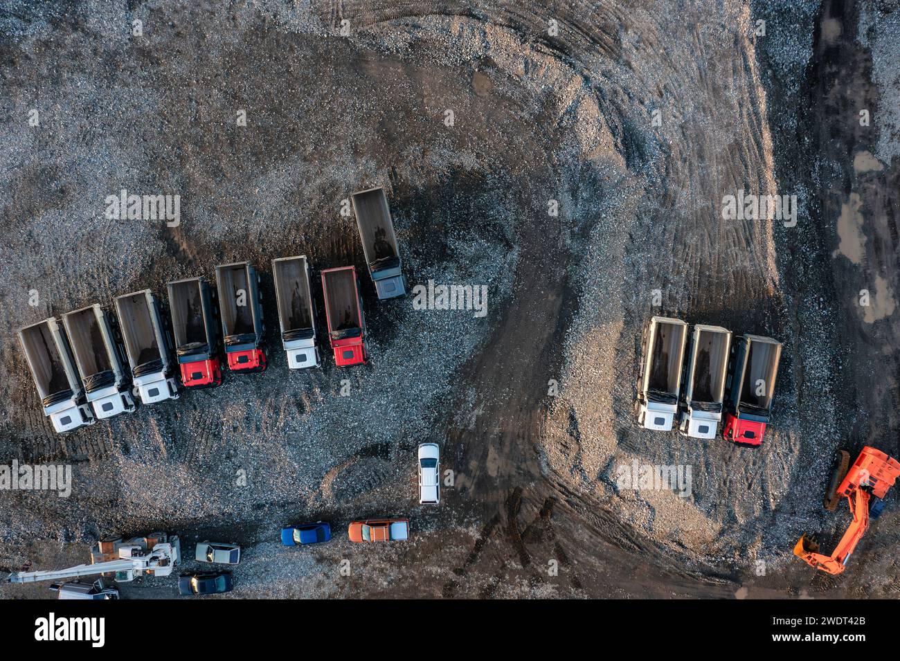 Aerial top down view of excavator and dump trucks during earthwork on construction site ...