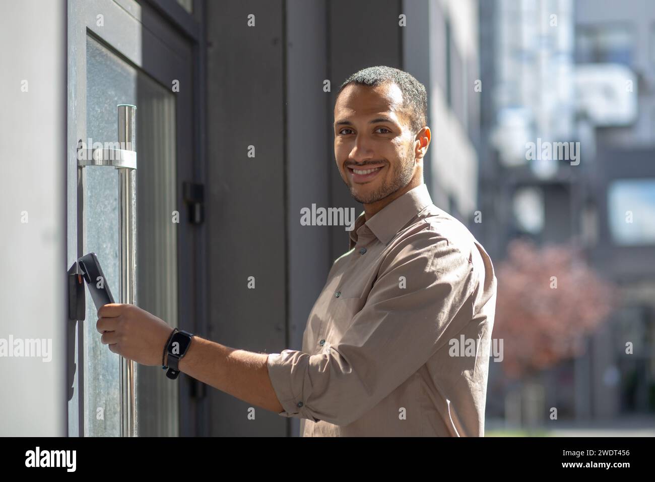 Cheerful young African American businessman entering office building ...