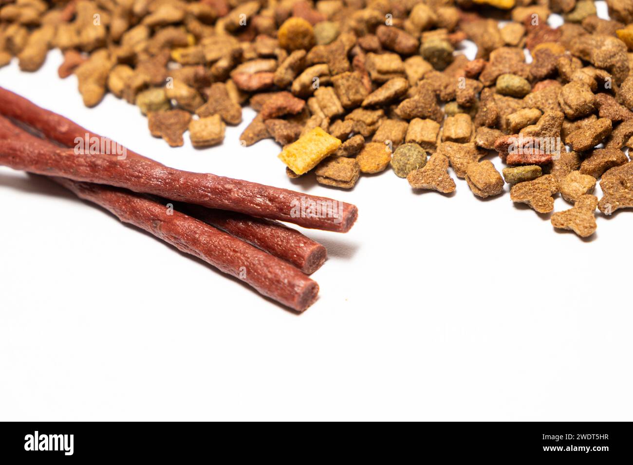 Treats for cats meat sticks sausages against the background of dry food ...