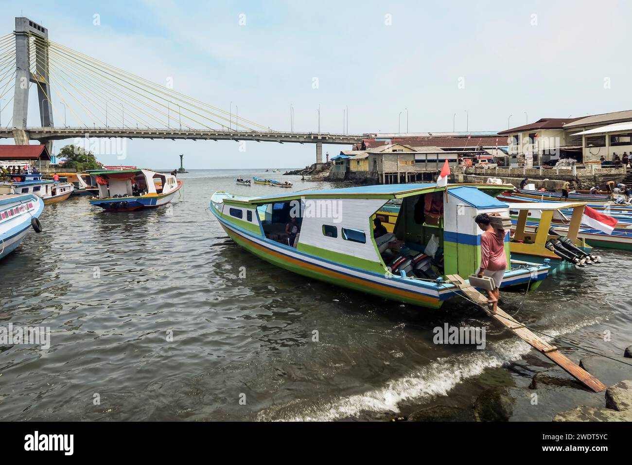 Covered ferry boats in Manado port with the Soekarno Bridge beyond in ...