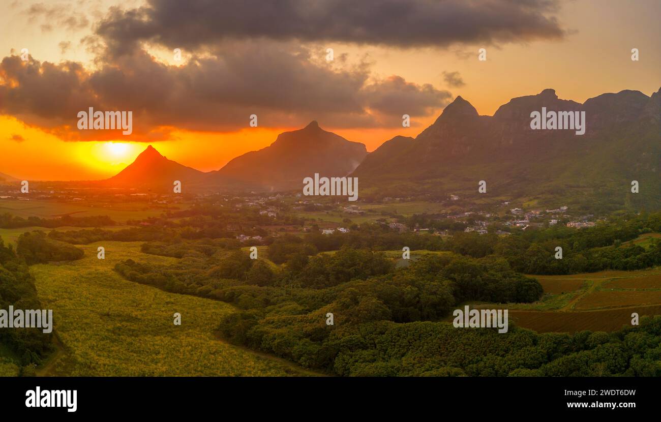 View of golden sunset behind Long Mountain and patchwork of green fields, Mauritius, Indian ...