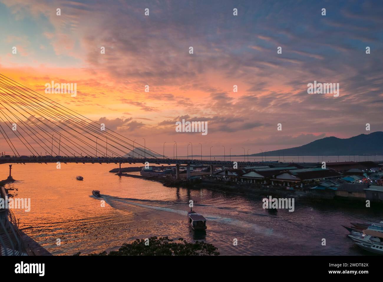 Manado port and Soekarno Bridge with Manadotua Island beyond at sunset ...
