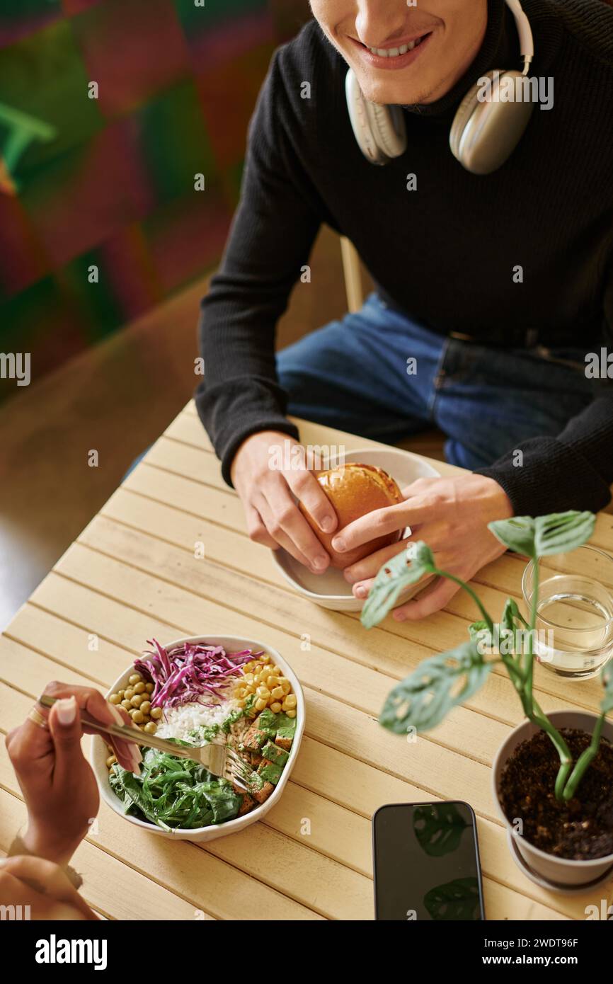 overhead view of young diverse couple enjoying vegan meal in cafe ...