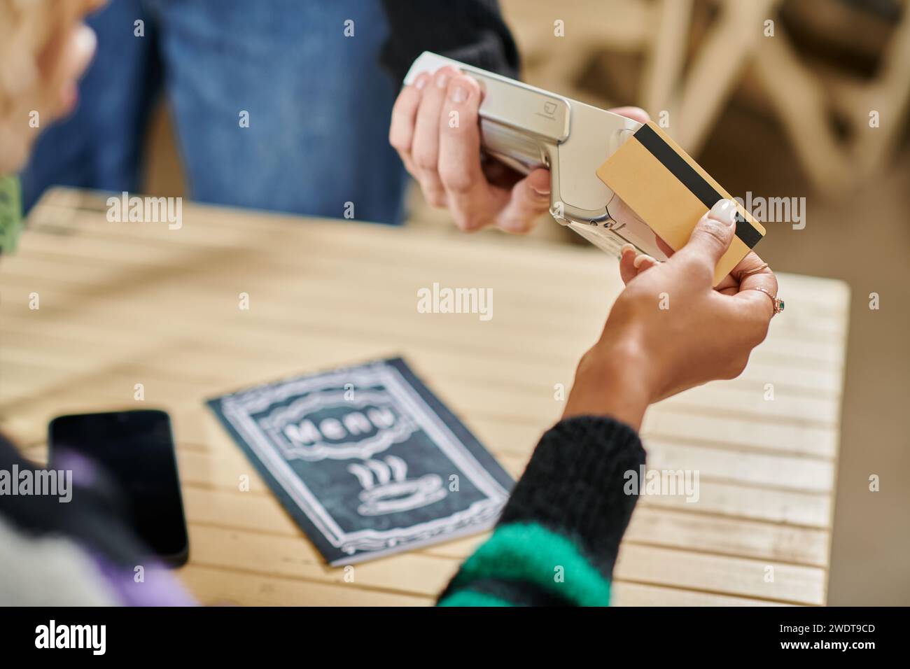 young customer holding credit card near card reader, cropped hand on ...