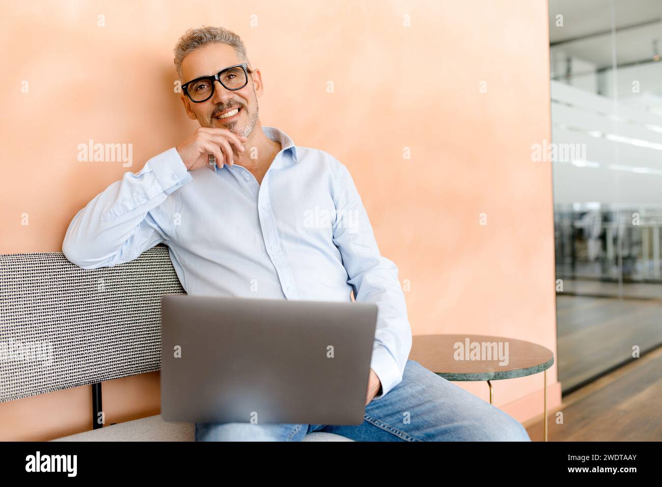 The businessman poses with his laptop, his cheerful demeanor and smart ...