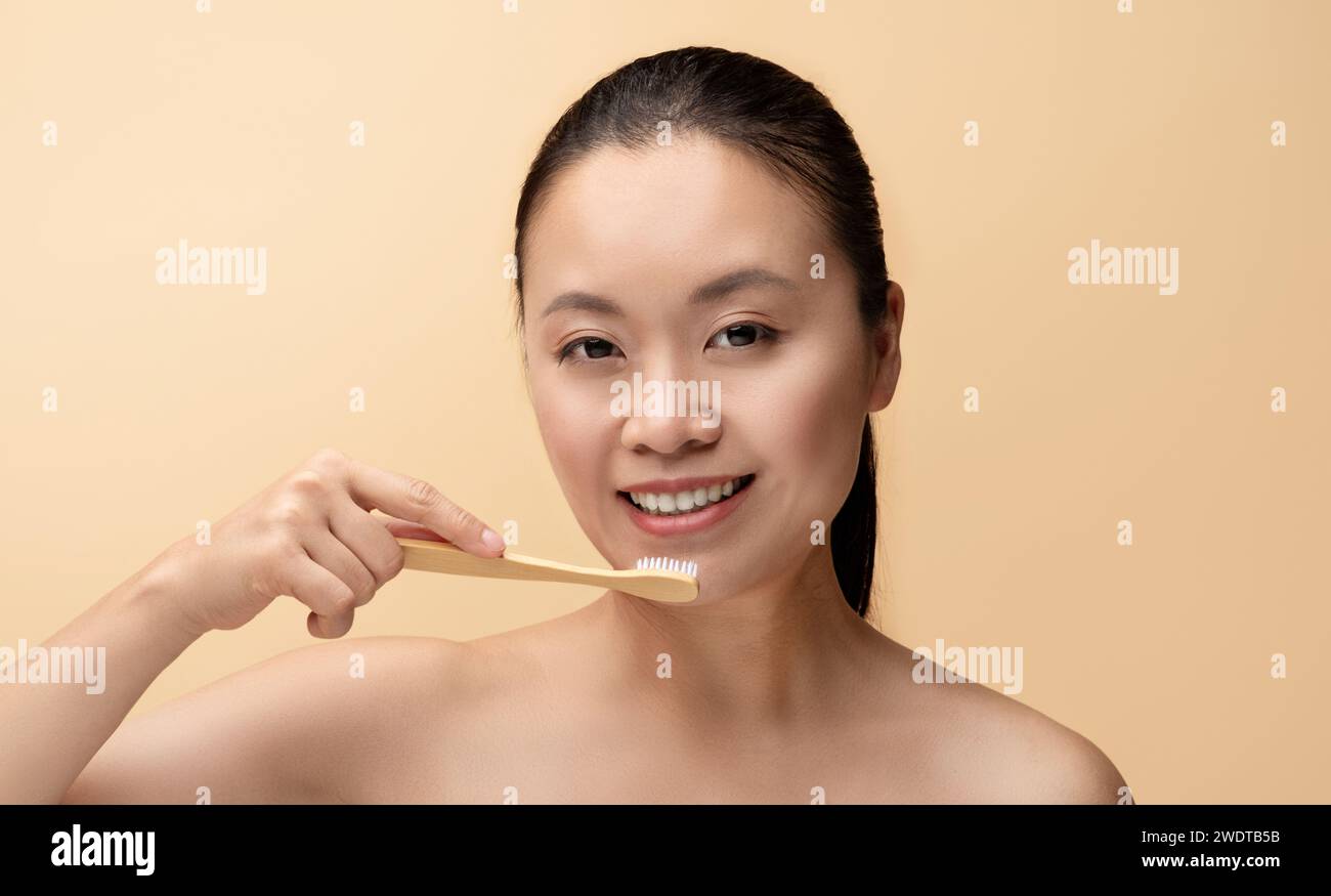 Cheerful millennial chinese woman with perfect smile, brushing teeth ...
