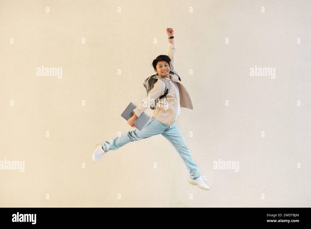 Excited young asian guy with laptop jumping in the air Stock Photo - Alamy