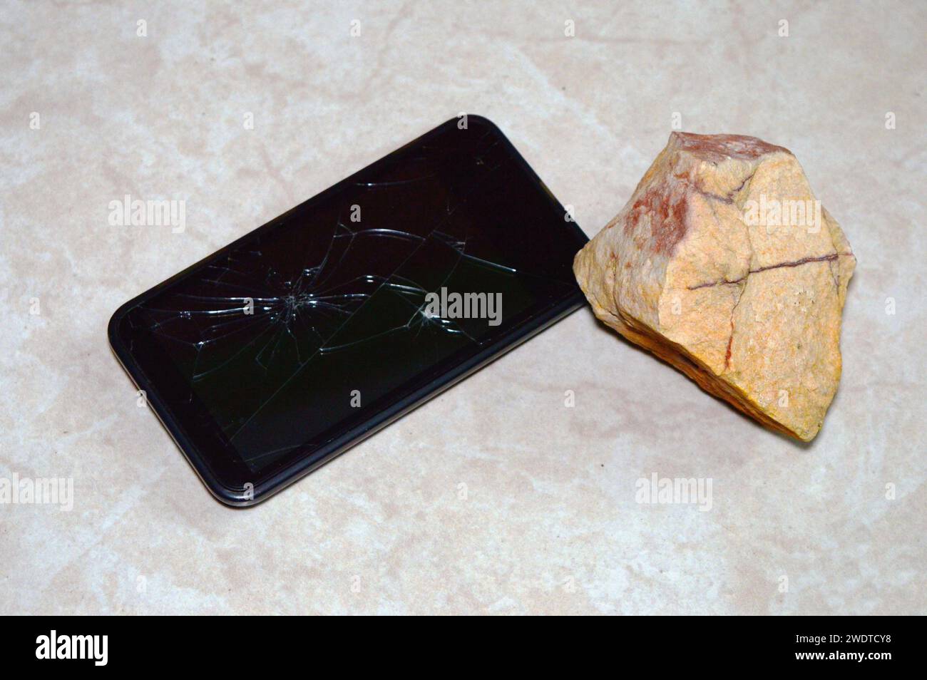 There is a stone and a broken phone on the floor - symbolizing breaking ...