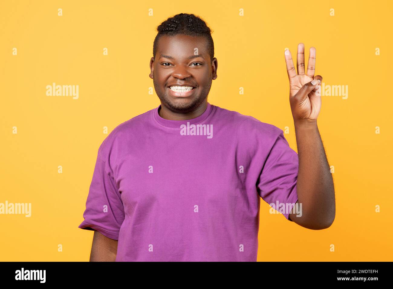 Cheerful African American guy raising hand showing three fingers ...