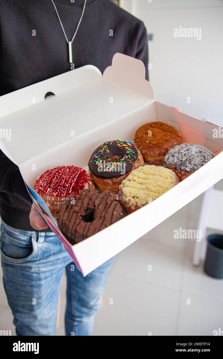 Man holding an open box of six assorted doughnuts standing Stock Photo ...