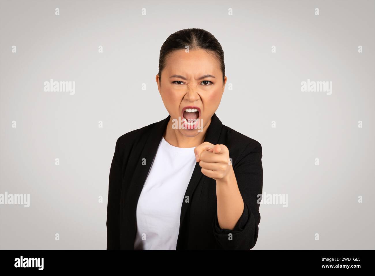 Angry Asian businesswoman pointing accusingly with a furious expression ...