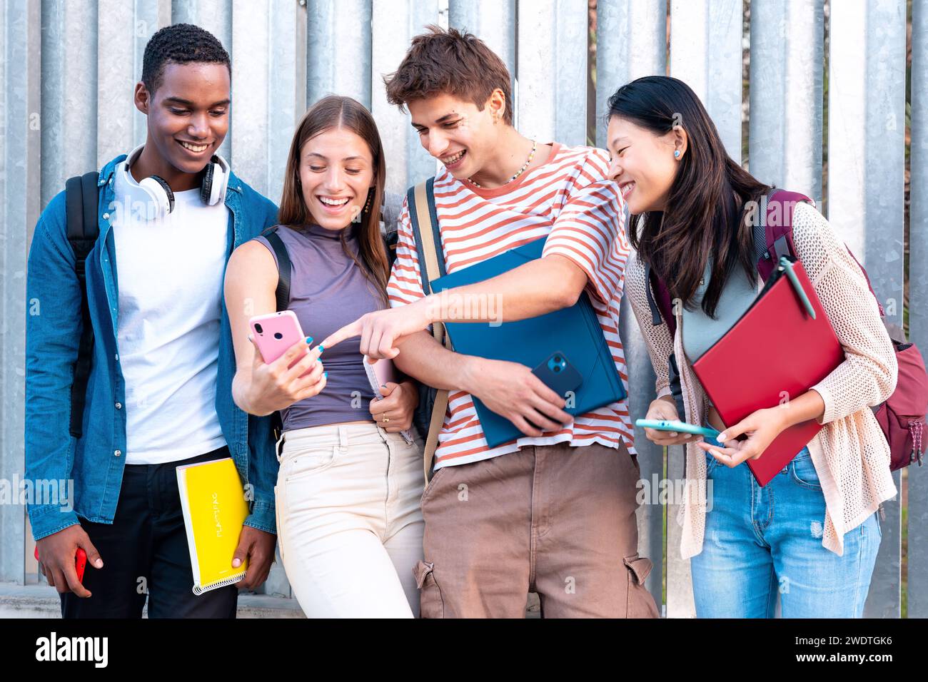Group of college students laughing, looking at social media on mobile ...
