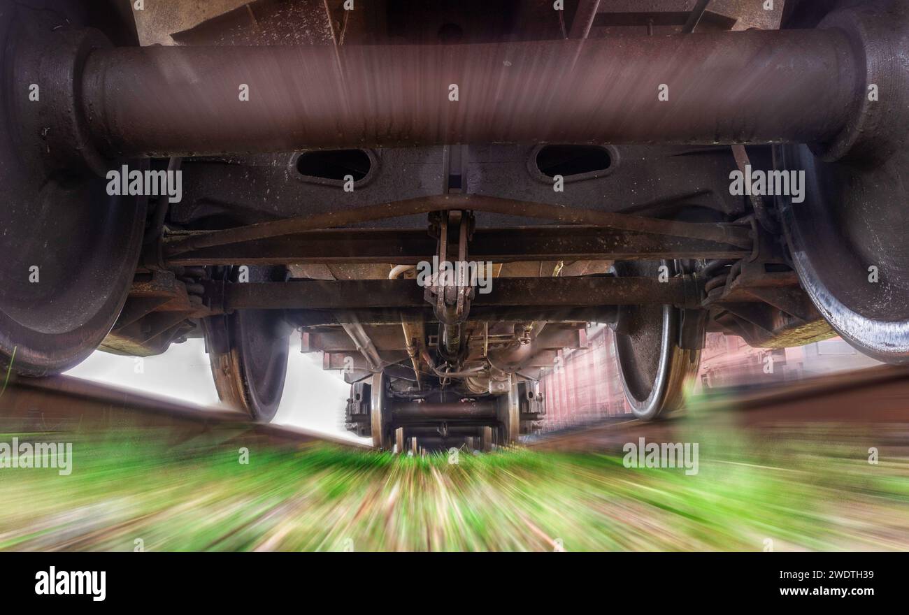 Freight train in motion. View under the train. Blurred background gives ...