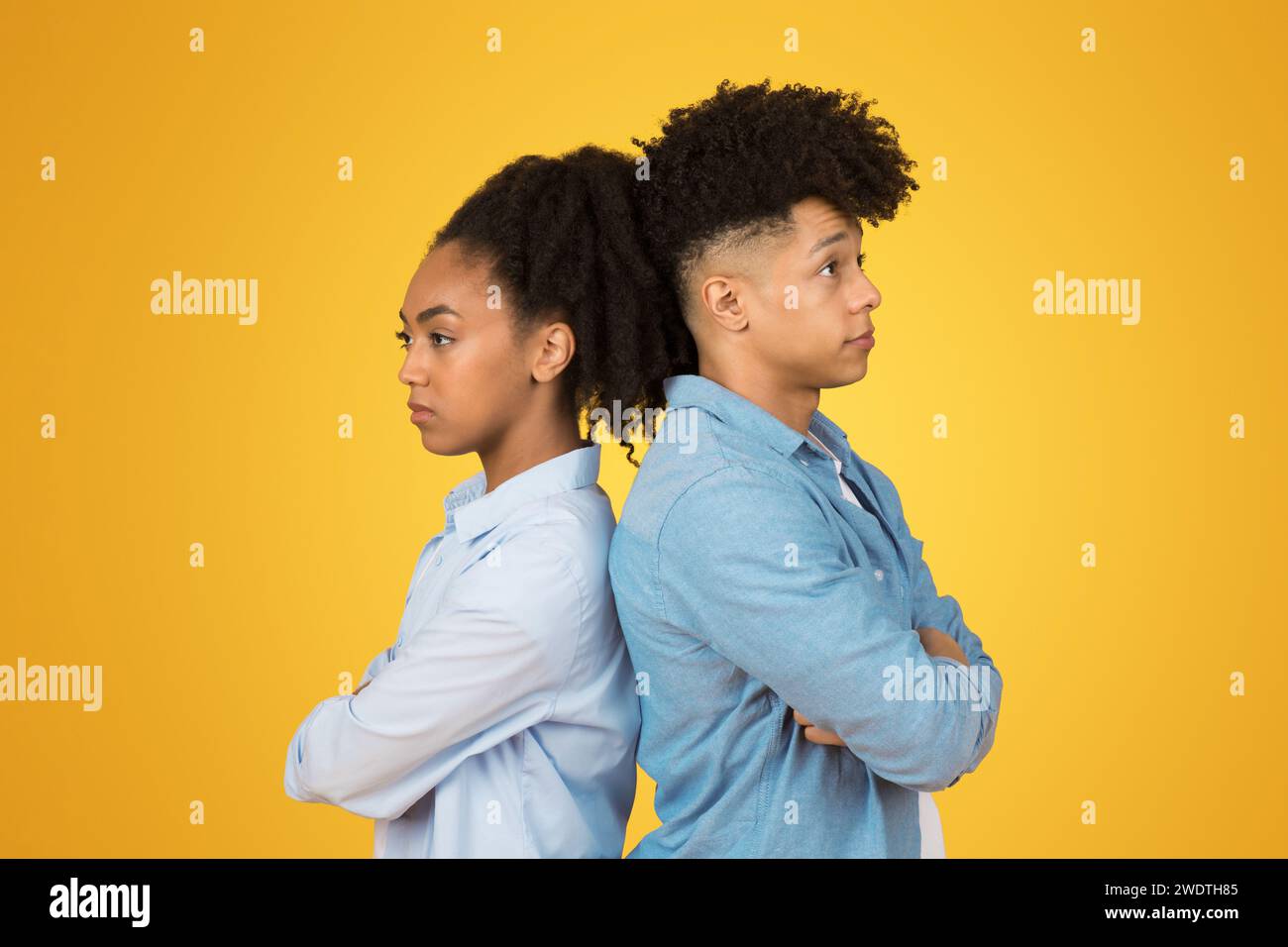 A teenage girl and boy stand back-to-back with arms crossed and ...