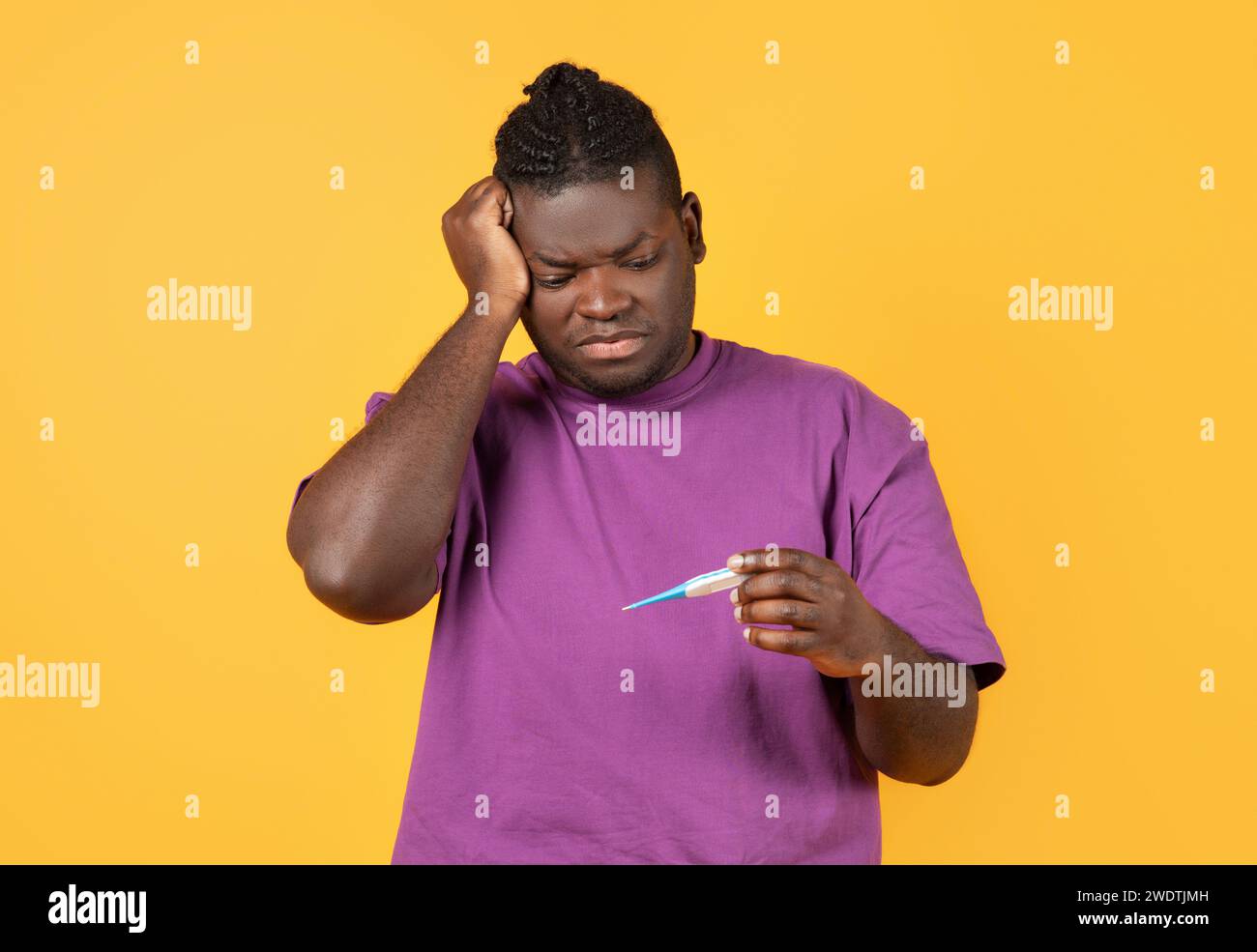 Sick black guy measuring temperature looking at thermometer, yellow ...
