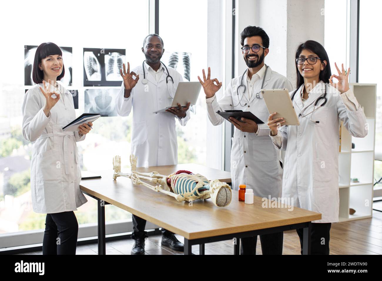 Medical students on anatomy lesson in modern classroom showing sign ok ...