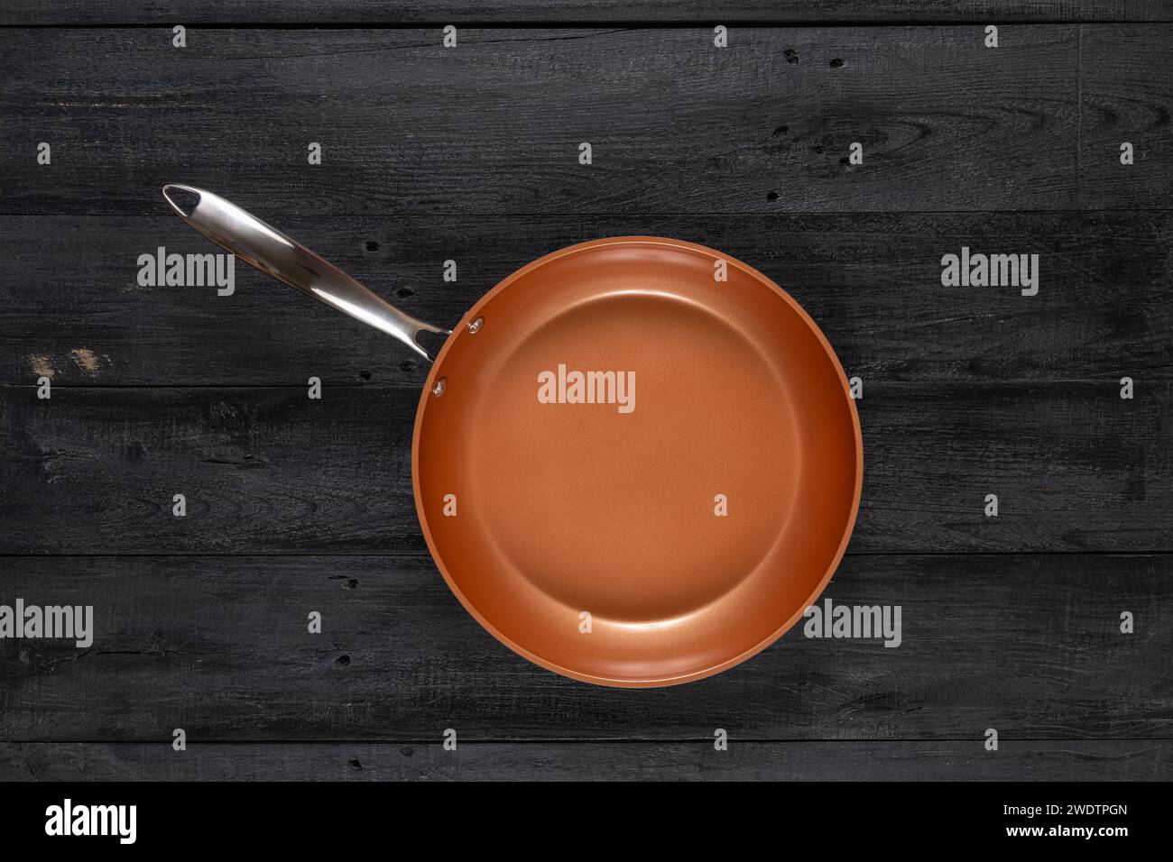 Round fry pan on a weathered black wood texture background. Non-stick ...