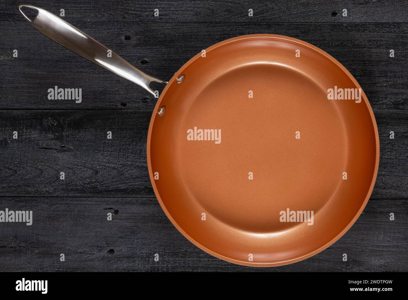 Round fry pan on a weathered black wood texture background. Non-stick ...