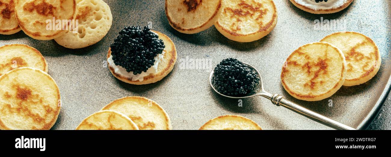 Blinis with black caviar and cream cheese panorama, on a festive dish ...