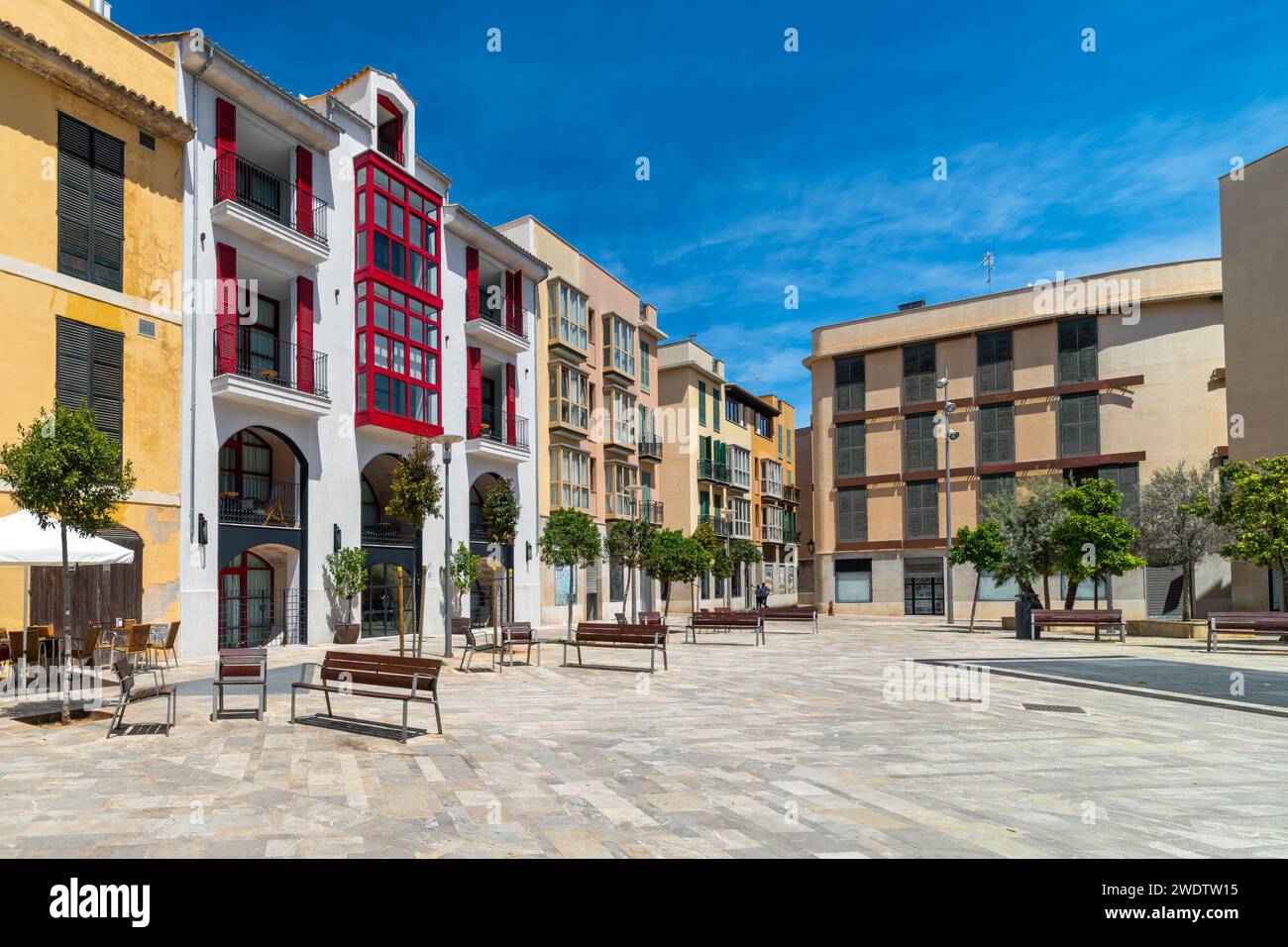 Colorful residential buildings and benches under blue sky on small town ...