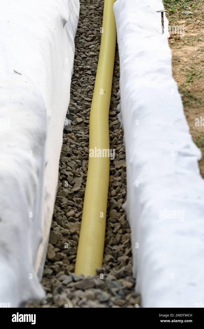 Yellow corrugated pipe with perforation in a trench with crushed stone ...
