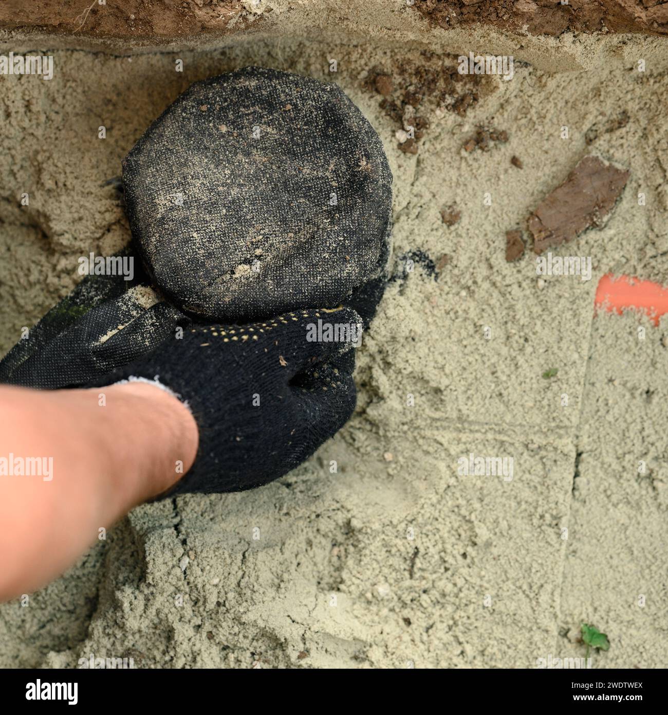 A plumber installs a reinforced orange sewer pipe during site ...