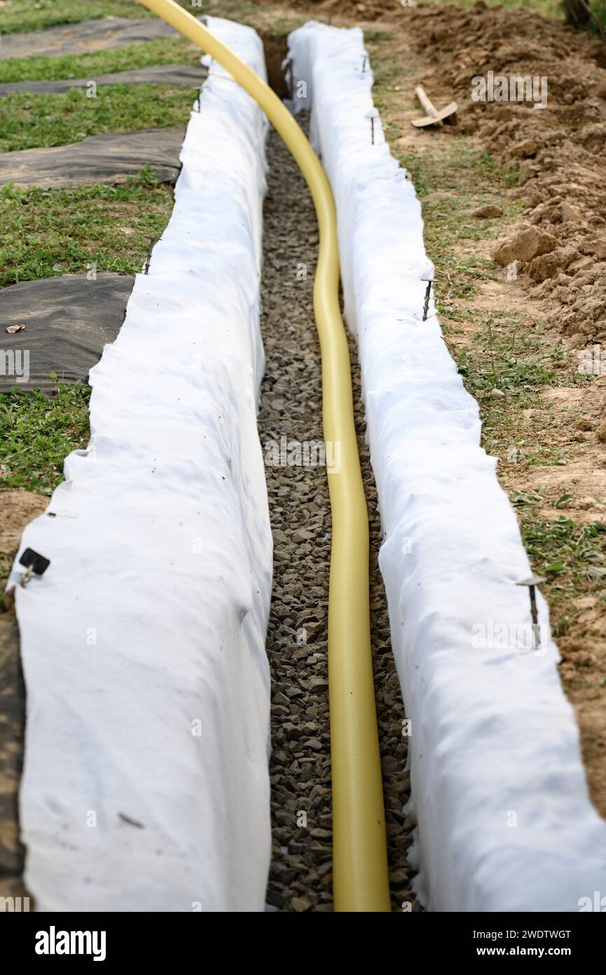 Yellow corrugated pipe with perforation in a trench with crushed stone ...