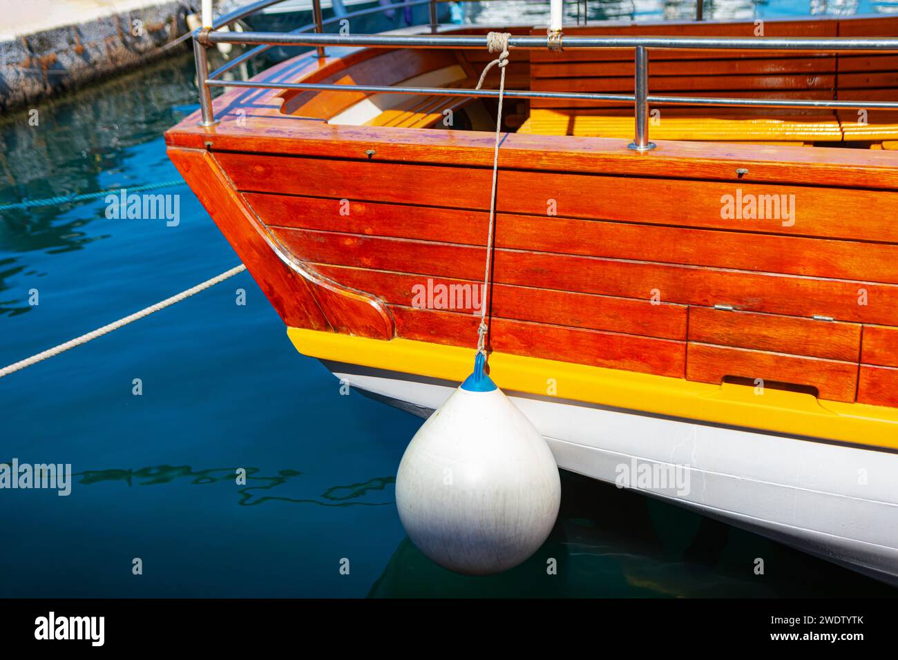 Detail of a wooden boat with in the port . Rubber fender protecting the ...