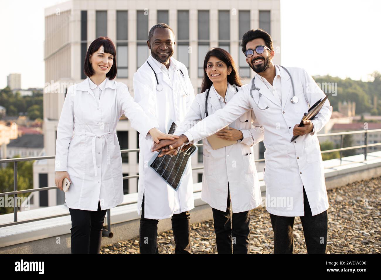 Medical specialists doctors looking at camera while stacking hands ...