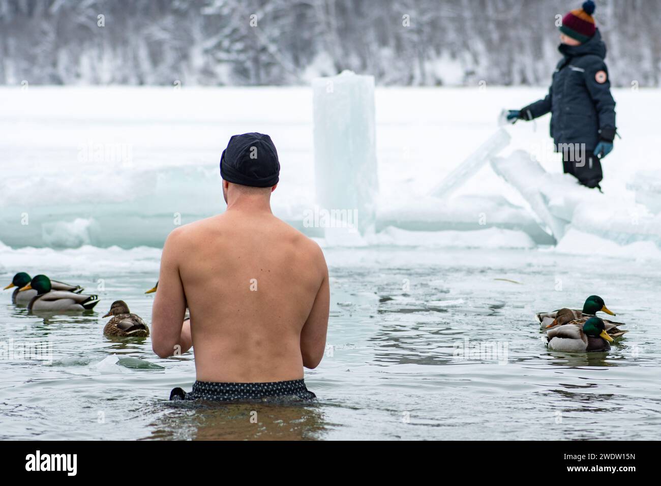 Boy or man with hat ice bathing in the freezing cold water of a frozen ...