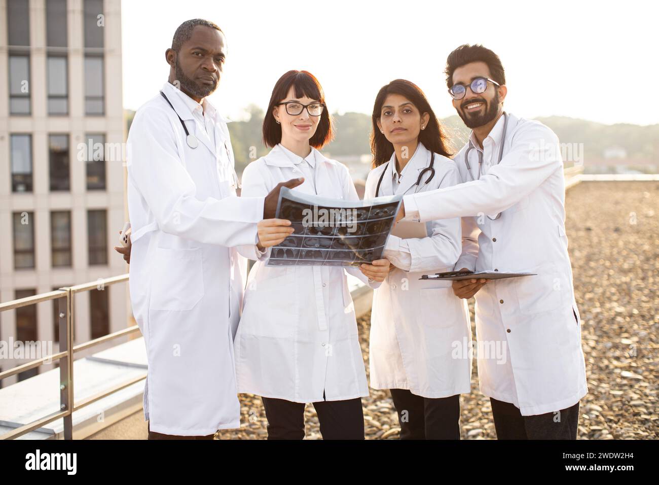 Multicultural doctors discussing patient's CT scan outside the hospital ...